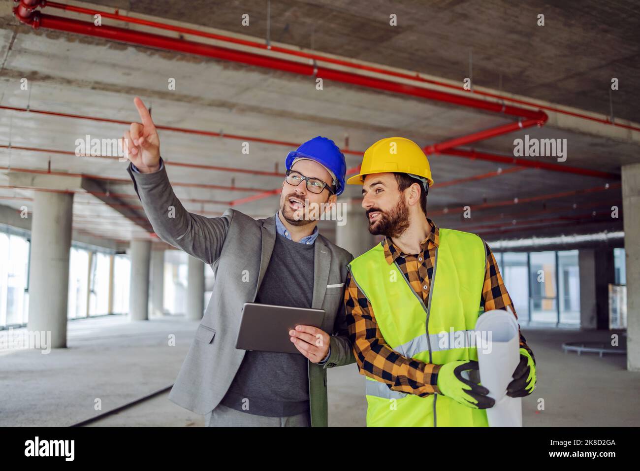Construction worker and architect standing in building in construction ...
