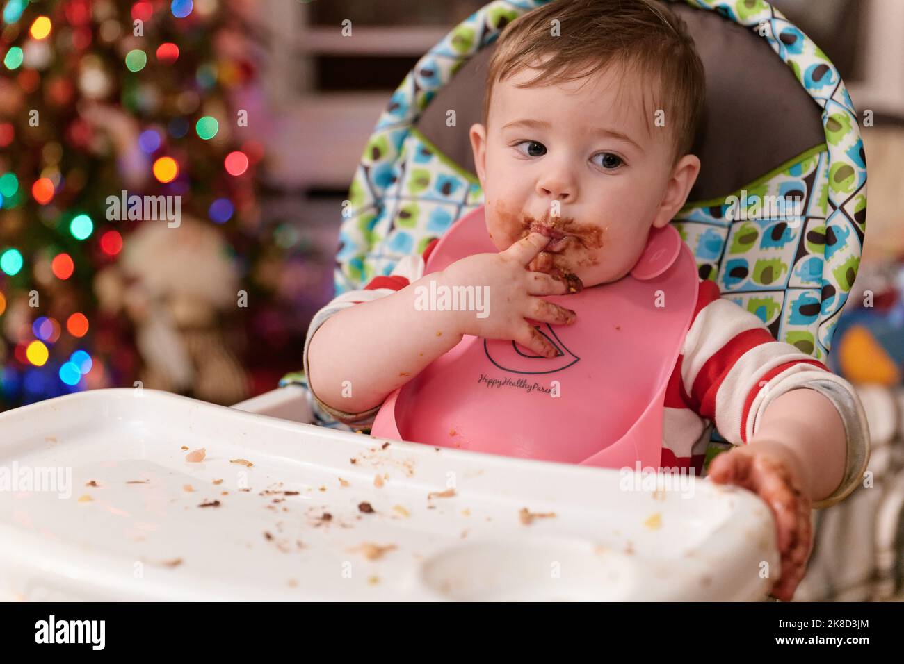 cute toddler eating chocolate candy in his high chair Stock Photo - Alamy