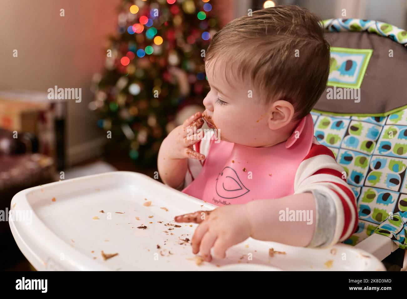 cute toddler eating chocolate candy in his high chair Stock Photo - Alamy