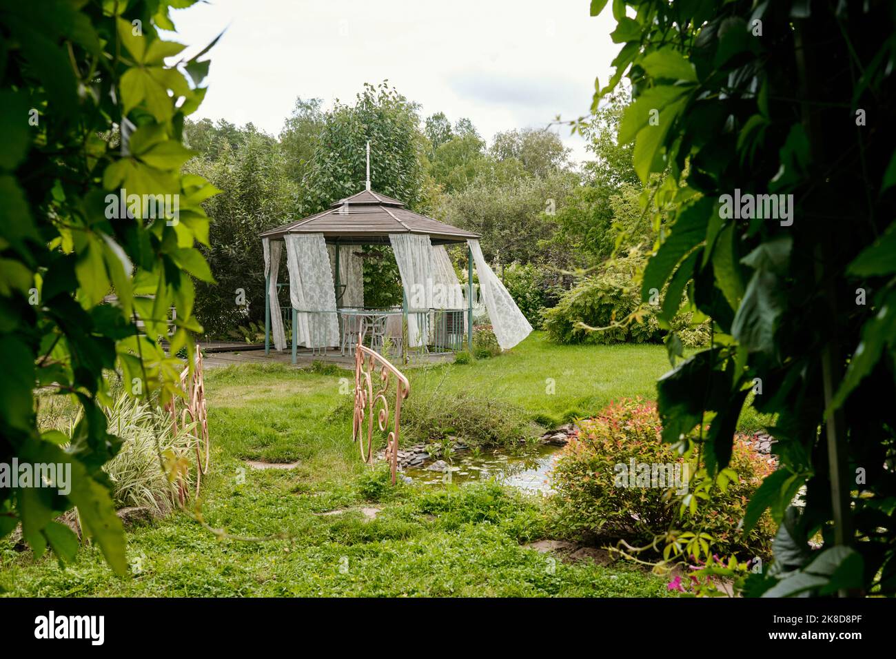 Small round alcove with white nylon curtains standing on backyard ...
