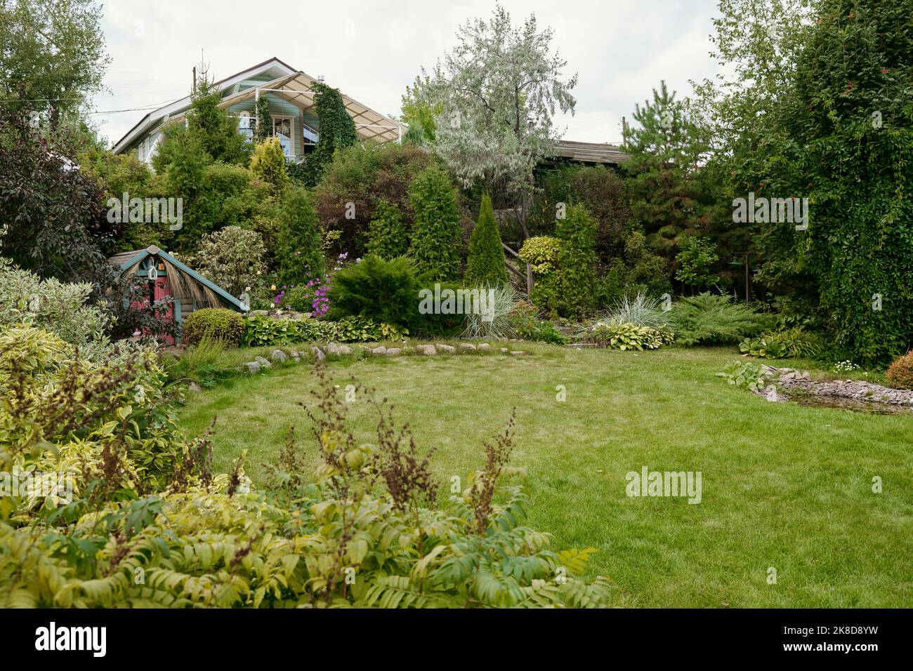 Wide green lawn surrounded by variety of plants, bushes and trees ...