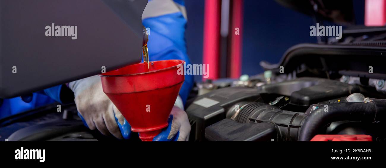Closeup hands of mechanic man pouring motor oil in engine car in the ...