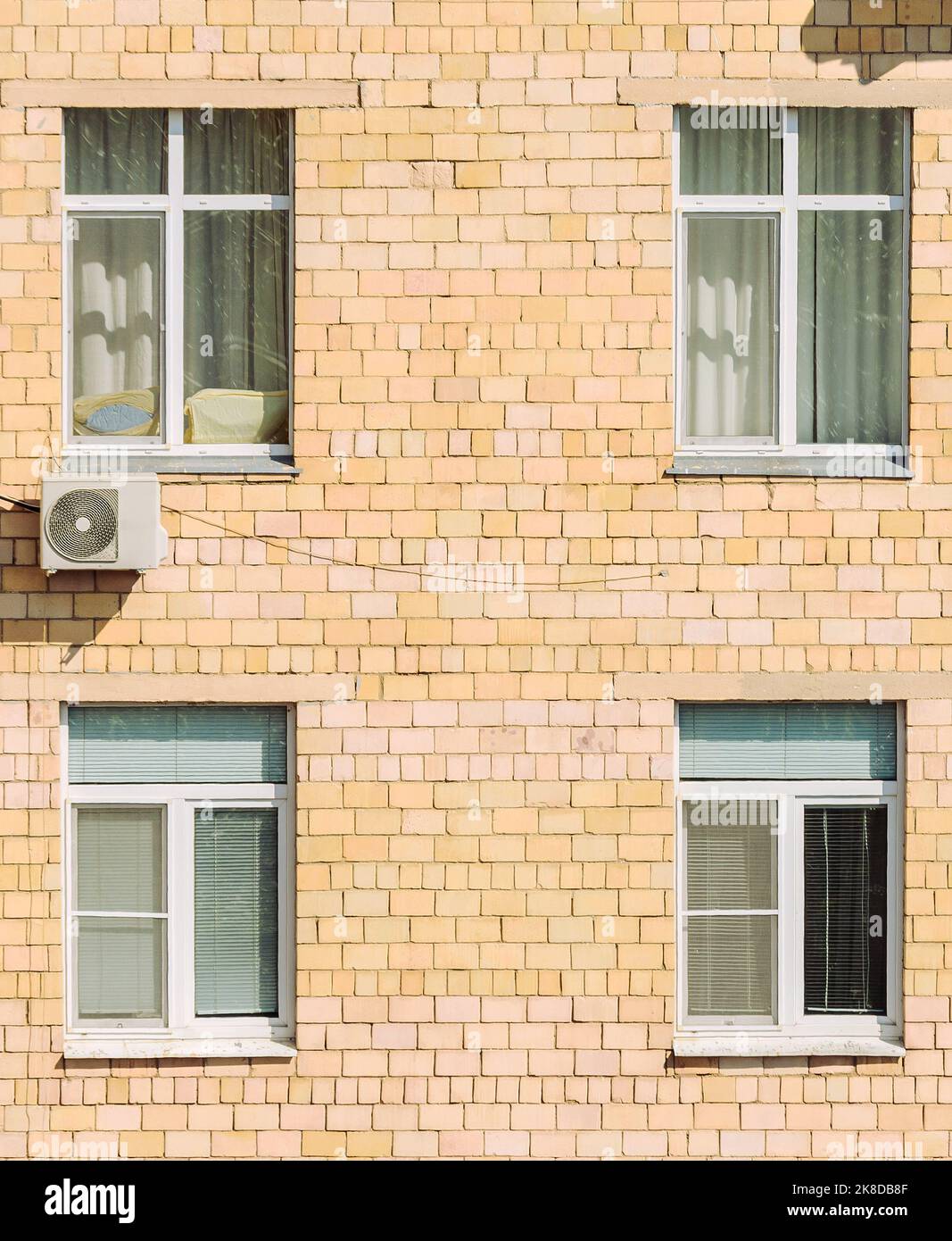 brick apartment building sunny facade wall with its plastic windows ...