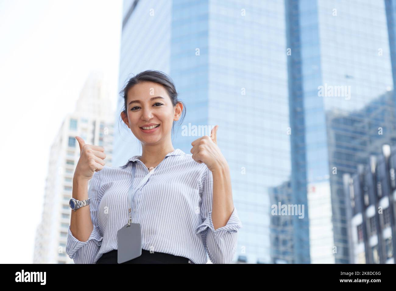 portrait of confident happy smiling young asian businesswoman showing thumbs up and standing ...