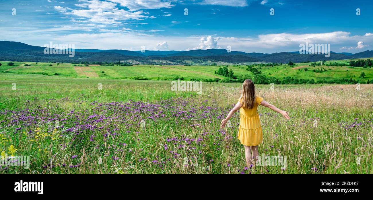 Woman in yellow dress staying at the green meadow in the mountain Stock ...