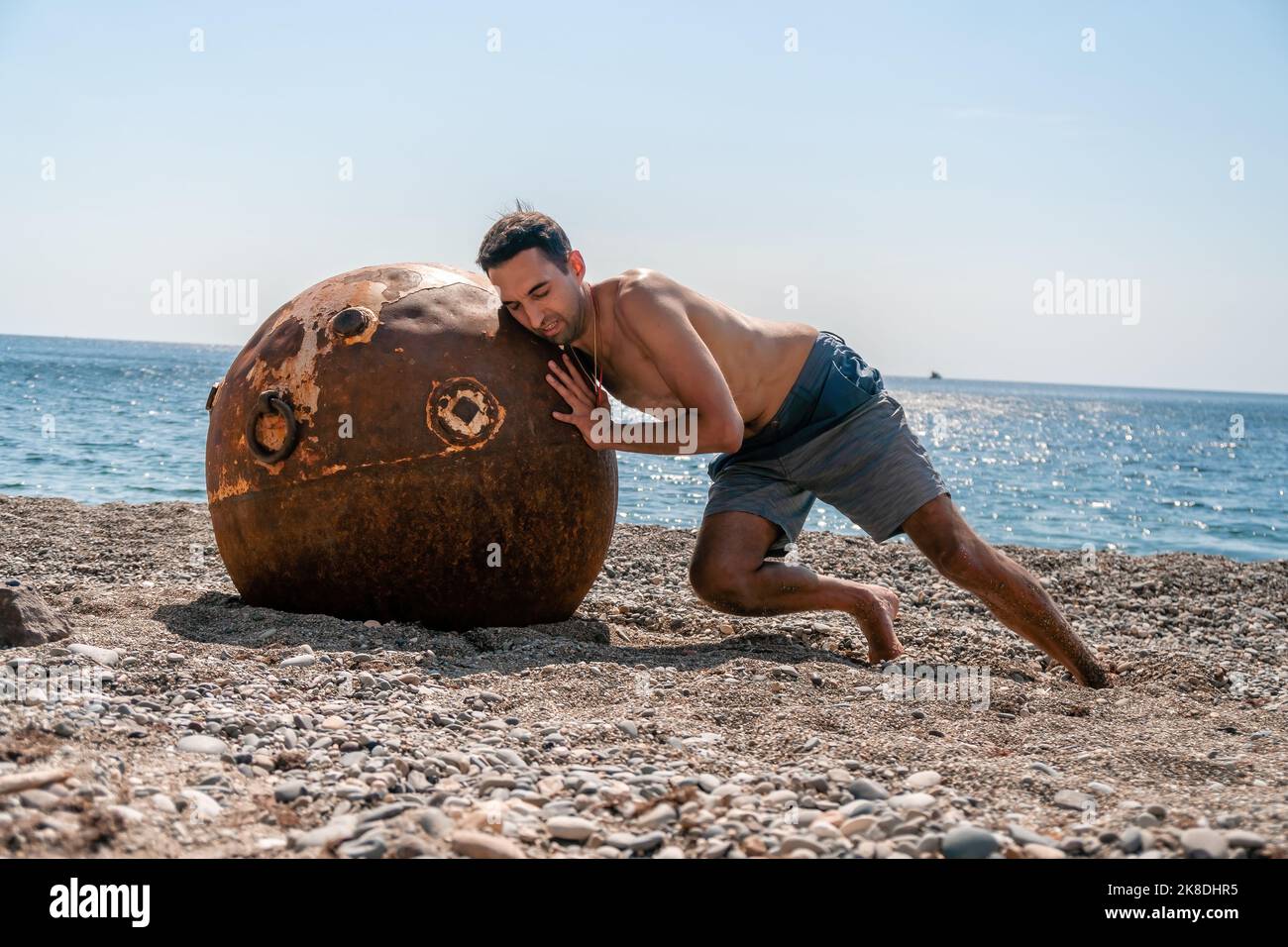 Man doing exercise outdoors near to old rusty floating marine mine on ...