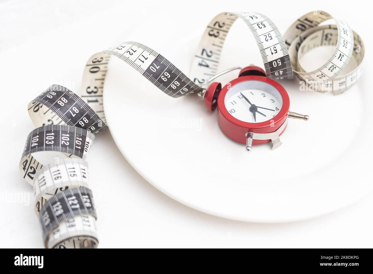 Time to lose weight concept. Red alarm clock with white plate and ...