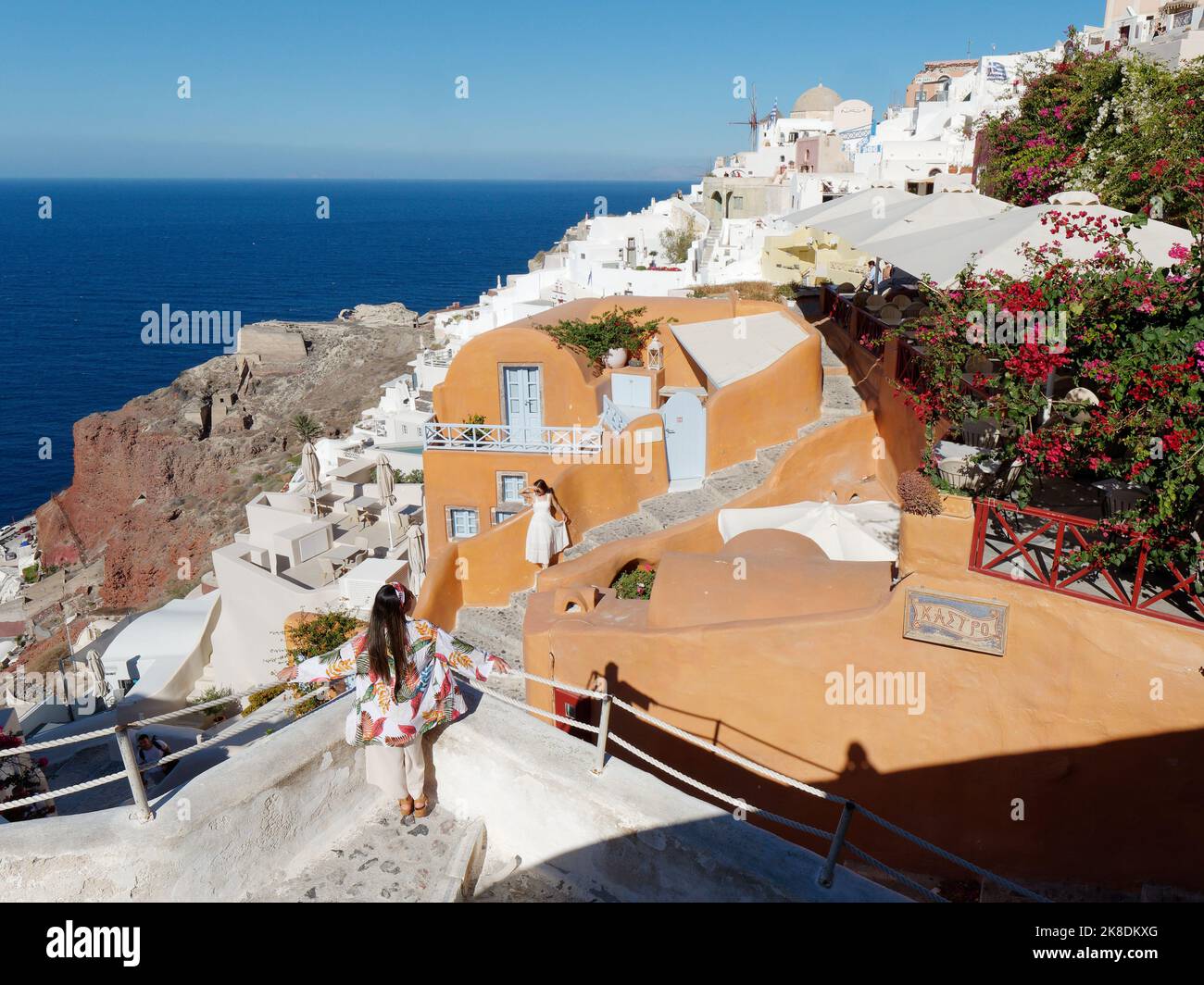 Town of Oia with tourists taking a photo in front of an orange building ...