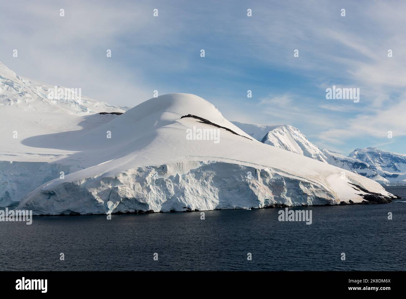 smooth dome shaped snow covered peak on shore of anvers island ...