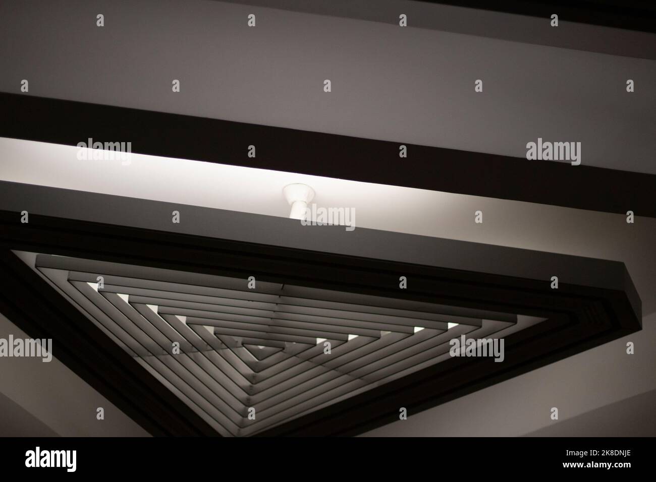 Triangular lamp in interior. Design of lighting device. Lamp on ceiling ...