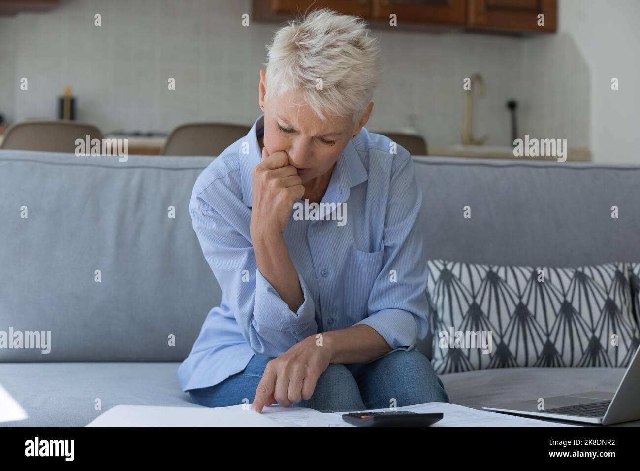 Upset older woman looking concerned while calculates expenses Stock ...