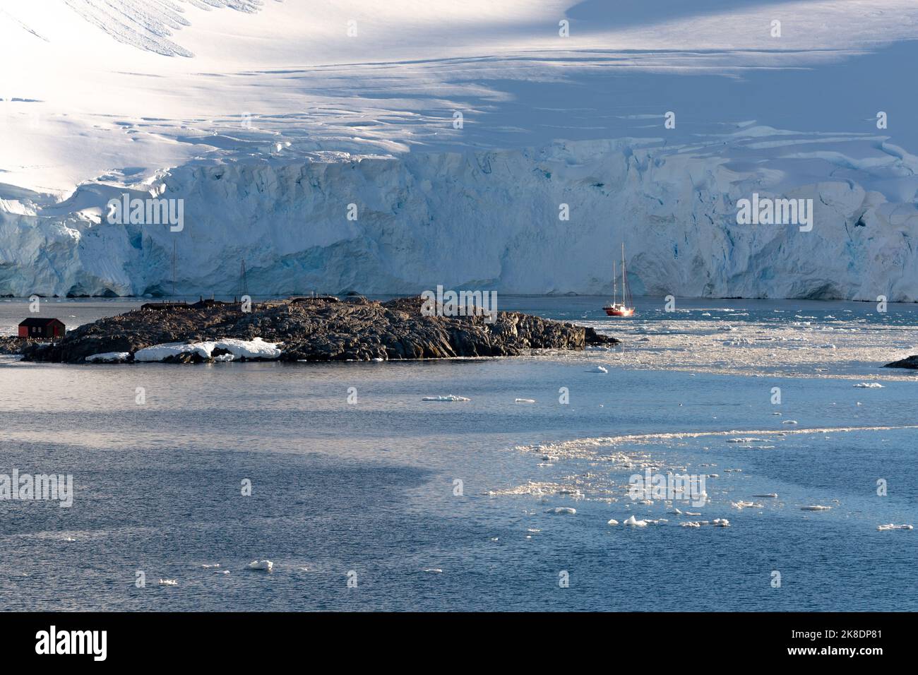 yacht moored in icy waters behind port lockroy station on rocky goudier ...