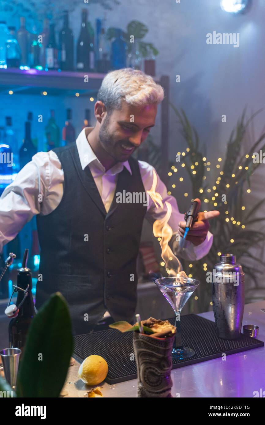 Professional barman making a tropical cocktail with fire flames at ...