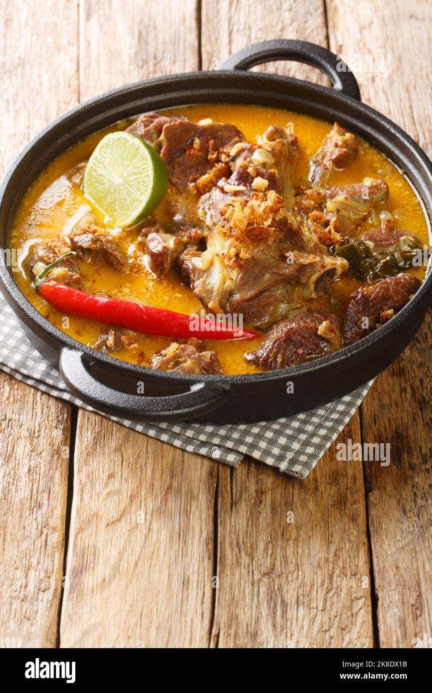 Spicy goat curry with coconut milk and spices close-up in a frying pan ...