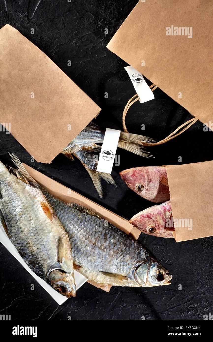 Salted air-dried roach and surmullets in kraft paper packets on black ...