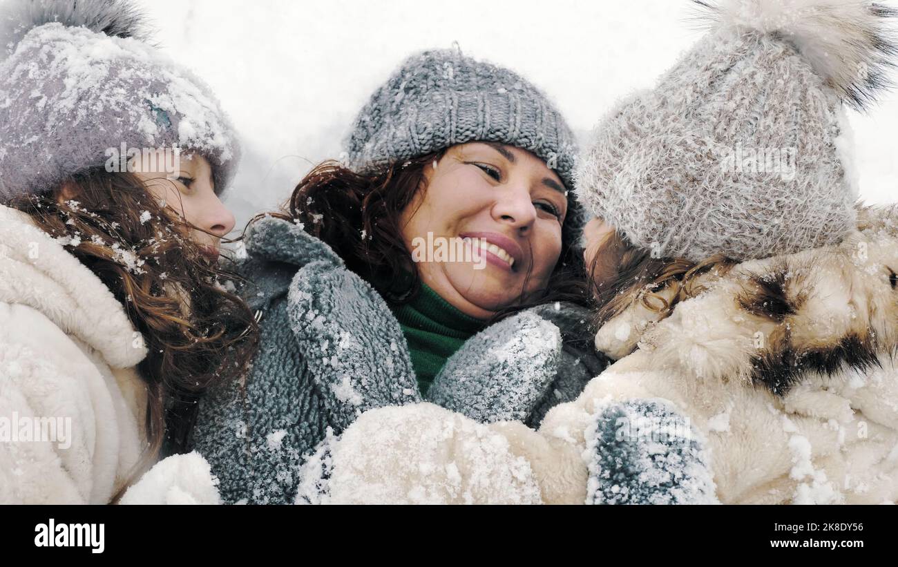winter family fun. Happy mother with little daughters are lieing ...