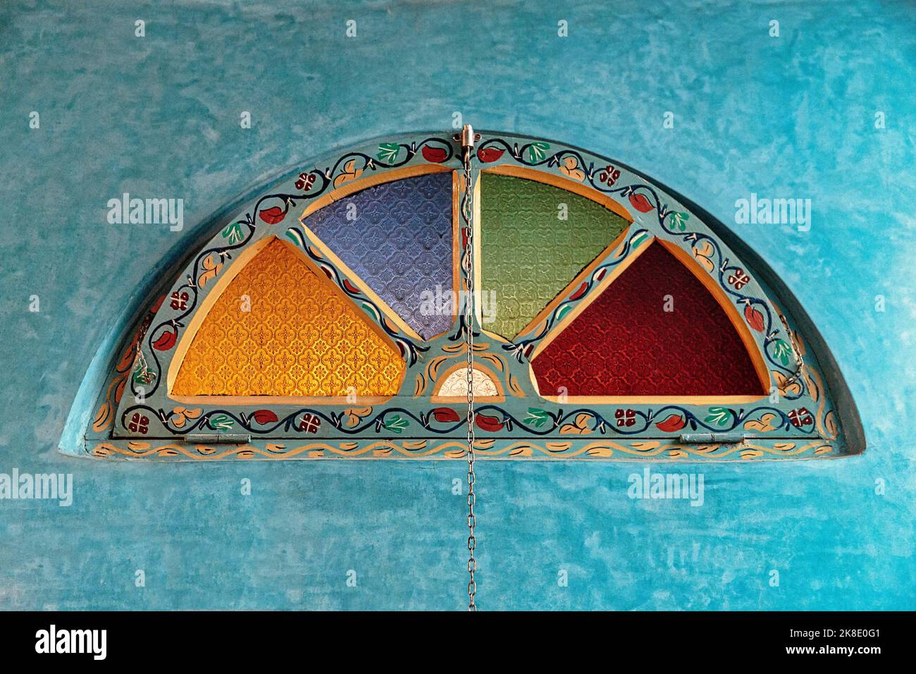 Decorated window with coloured glass in turquoise wall, semicircle ...