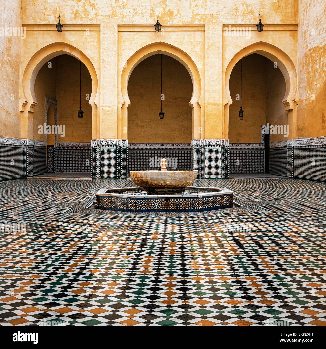 Fountain in front of arcades in the courtyard, coloured tile mosaics ...
