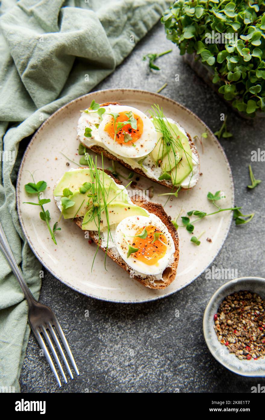 Bread toast, boiled eggs, avocado slice, microgreens on a plate ...