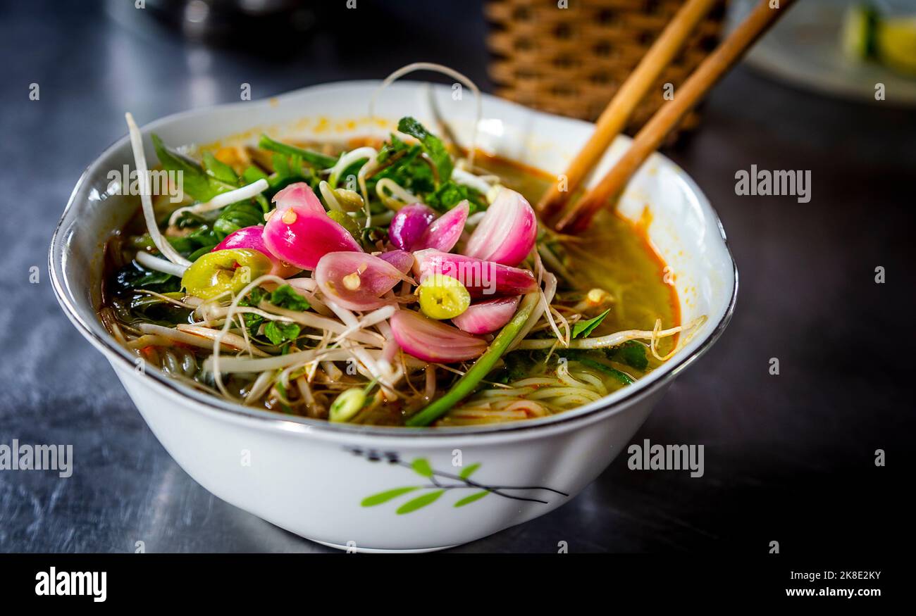 White bowl of Vietnamese Bun Cha with vegetables on top and chopstick ...