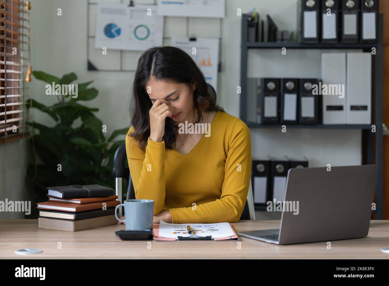 Stressed Asian business woman worry with many document on desk at ...