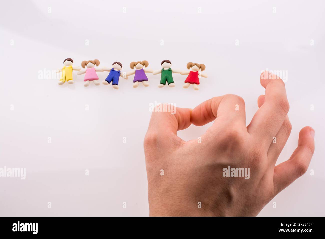 Hand near colorful dressed children figures on a white background Stock ...