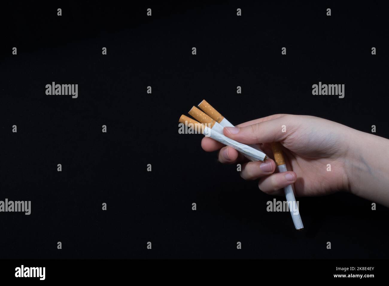 Hand is holding cigarettes on black background Stock Photo - Alamy
