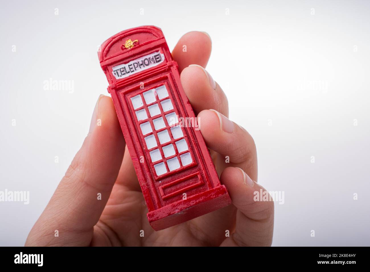 Hand holding a red color phone booth on a white background Stock Photo ...