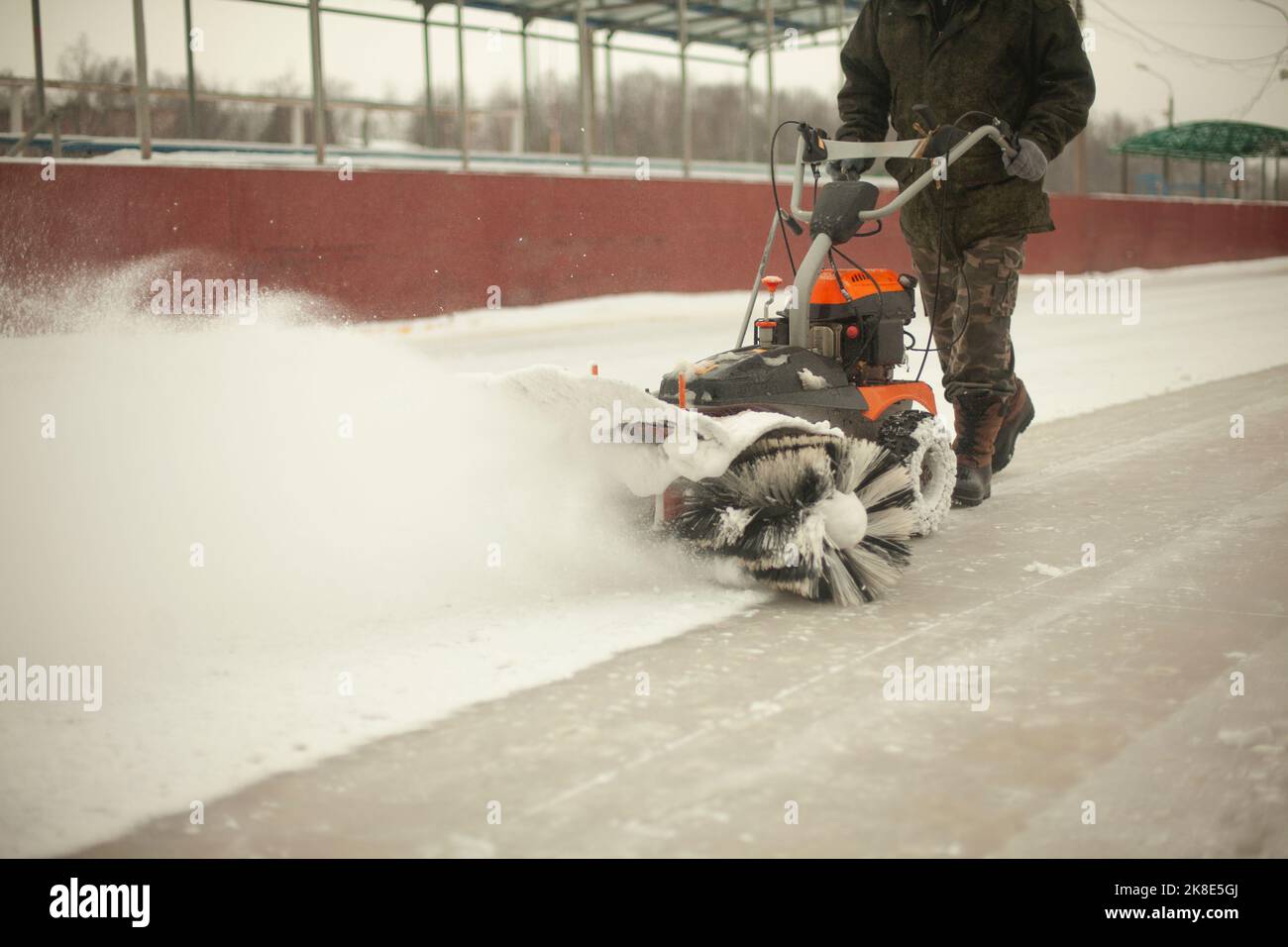 Snow removal at ice rink. Removal of layer of snow from ice. Worker ...