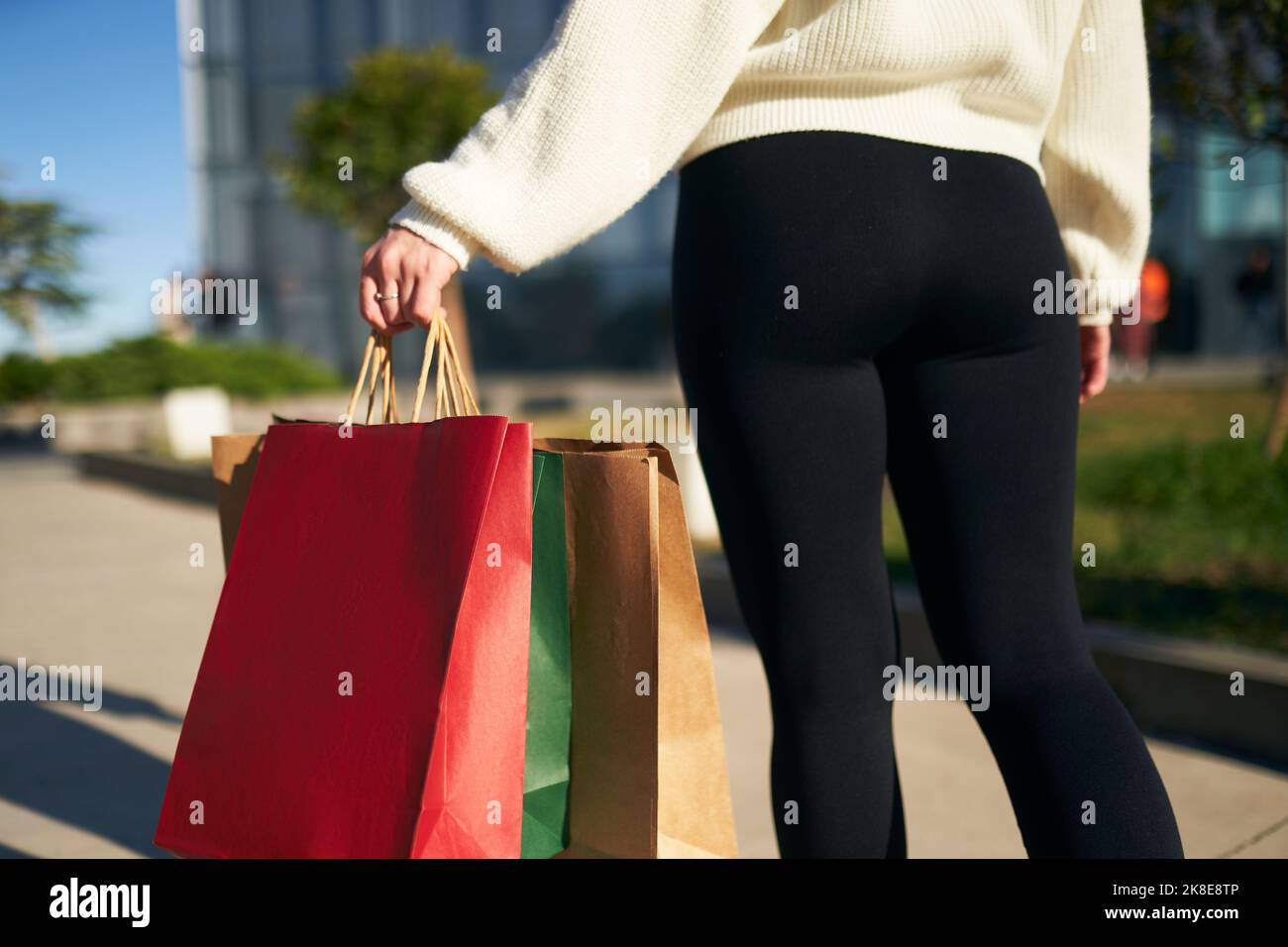 Close up of woman walking with shopping bags in hands in city from mall ...