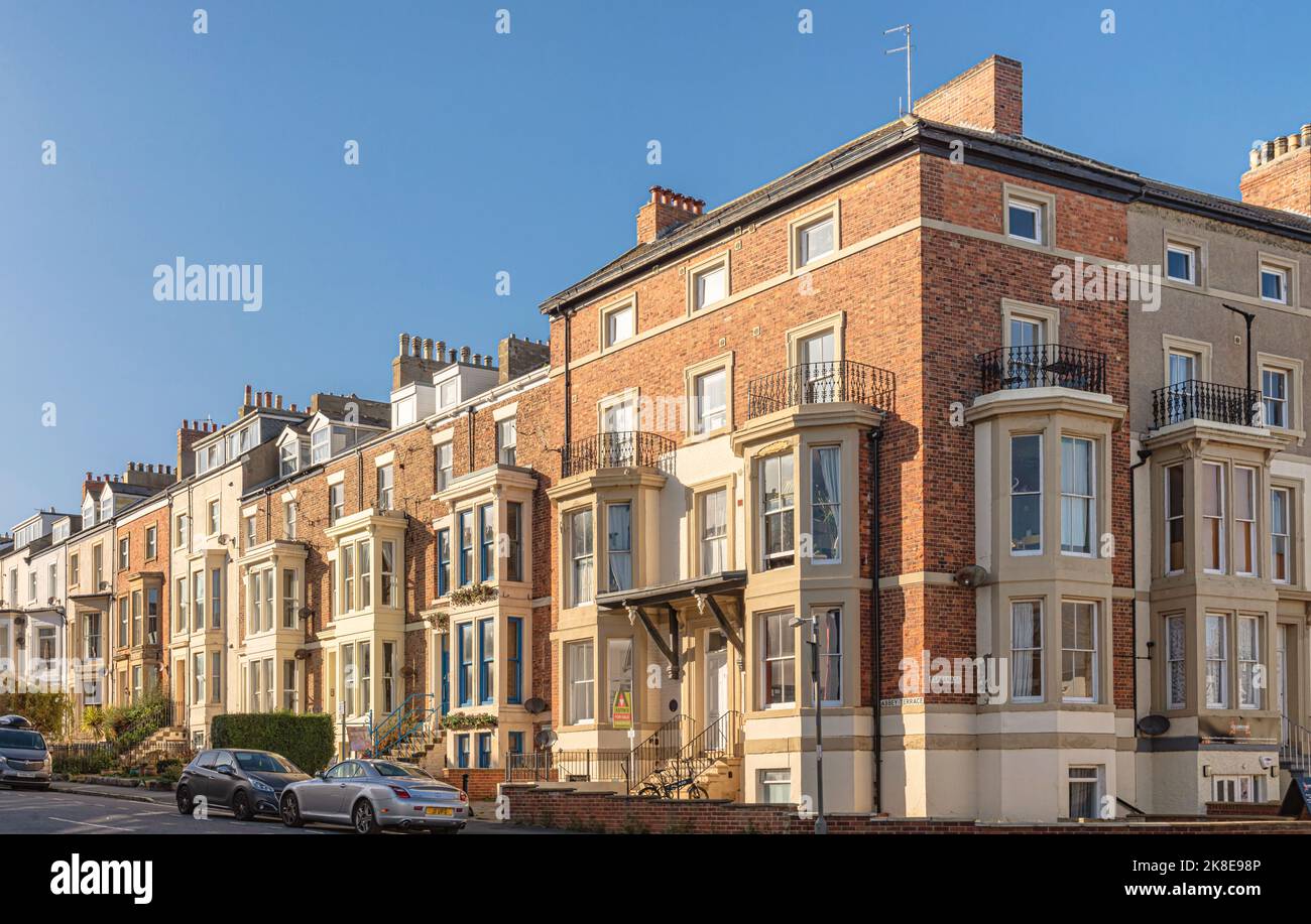 A street of brick built seaside boarding houses. Cars are parked in the ...