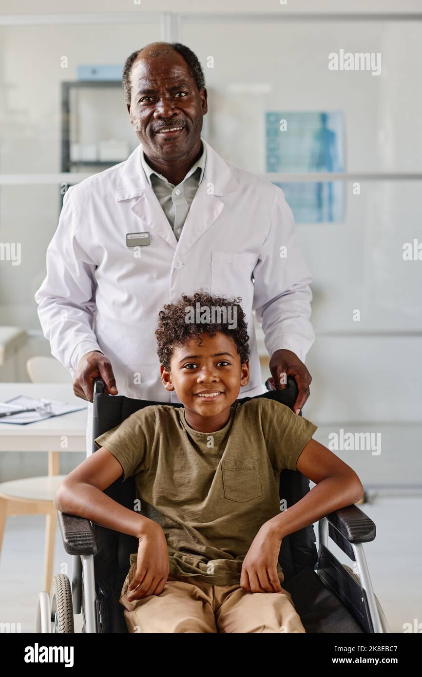 Portrait of African mature doctor with patient with disability standing ...