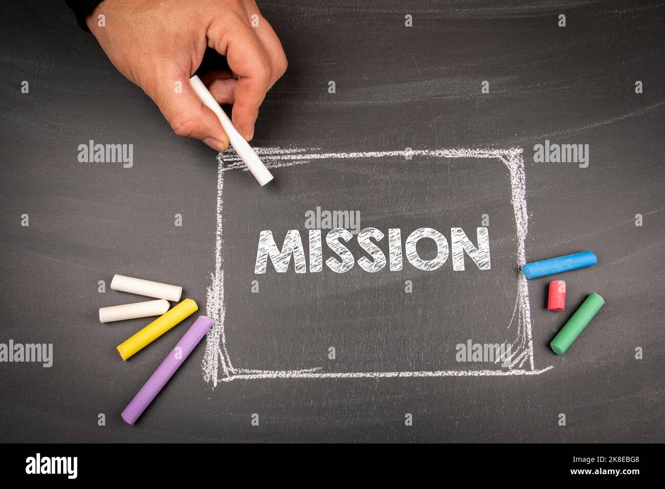 Mission. Text, drawn frame and hand with piece of chalk on blackboard ...