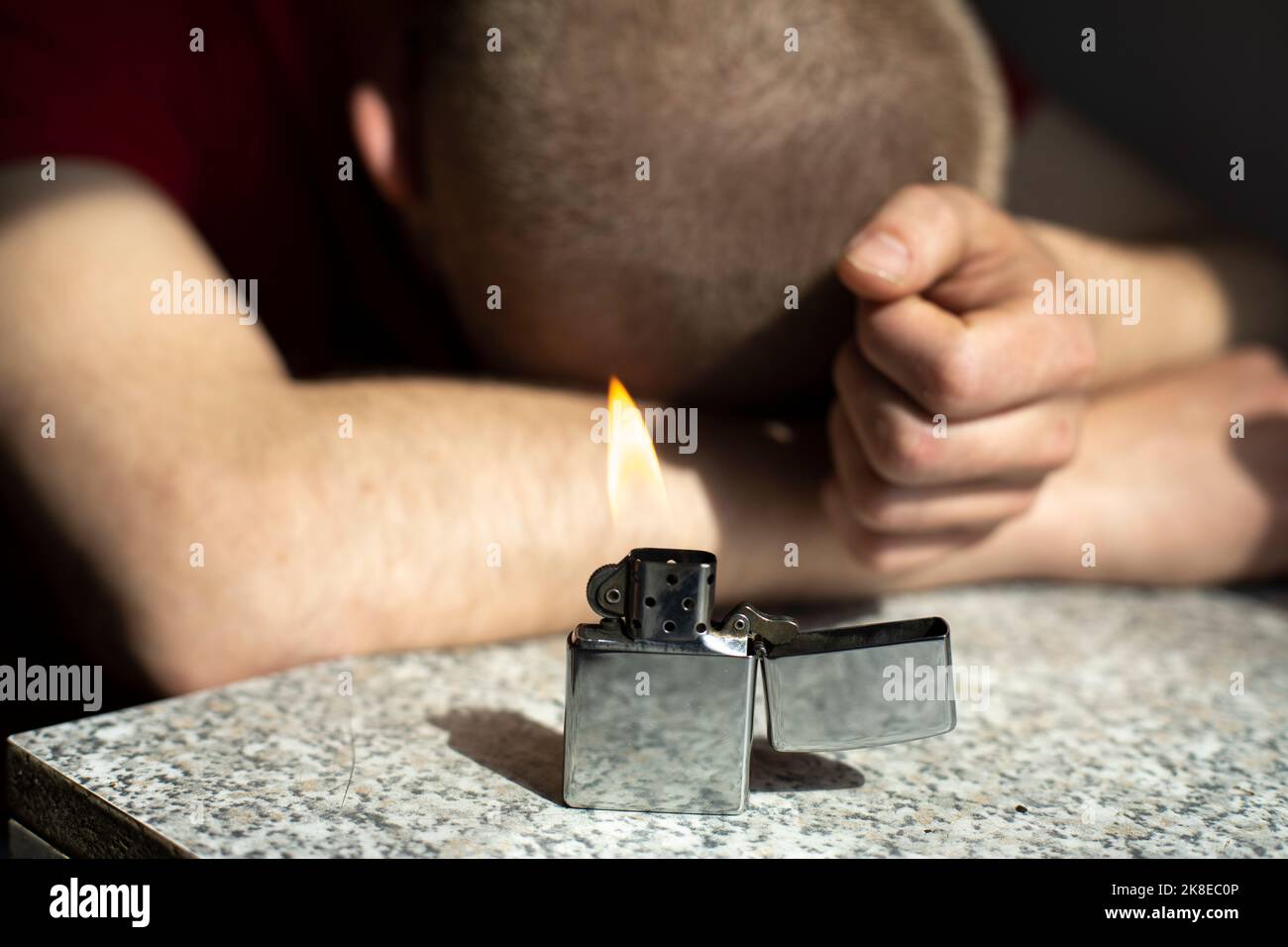 Gasoline lighter burns on table. Fire in background of sleeping guy ...