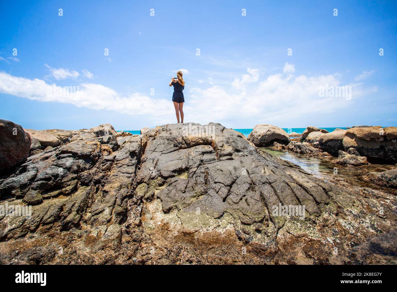 A female tourist takes a photo with her phone on the beach in the ...