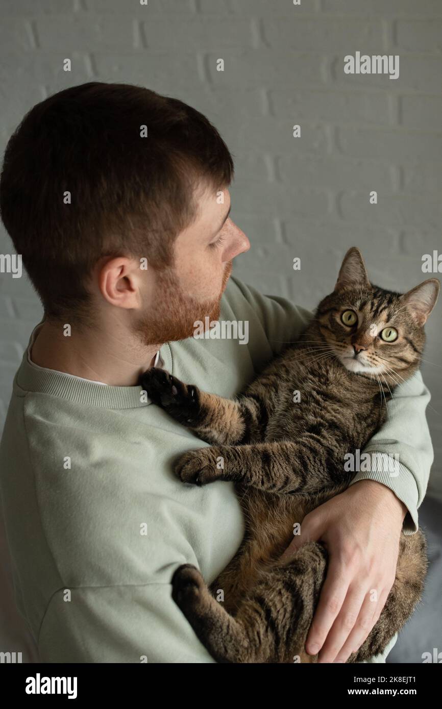 young man holds his cat in his arms. vertical photo Stock Photo - Alamy