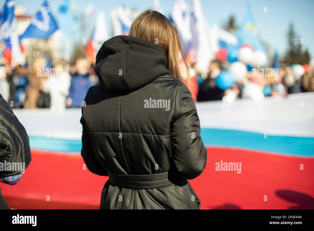 Man at rally in Russia. Girl stands against background of people with ...