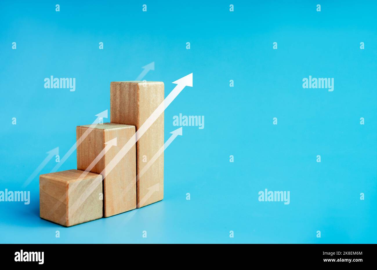 Shining rise up arrow on wooden cube blocks, bar graph chart steps on blue background, business ...
