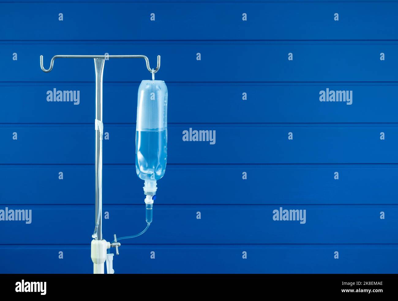 Saline bag hanging on poles stand isolated on blue wood plank wall ...