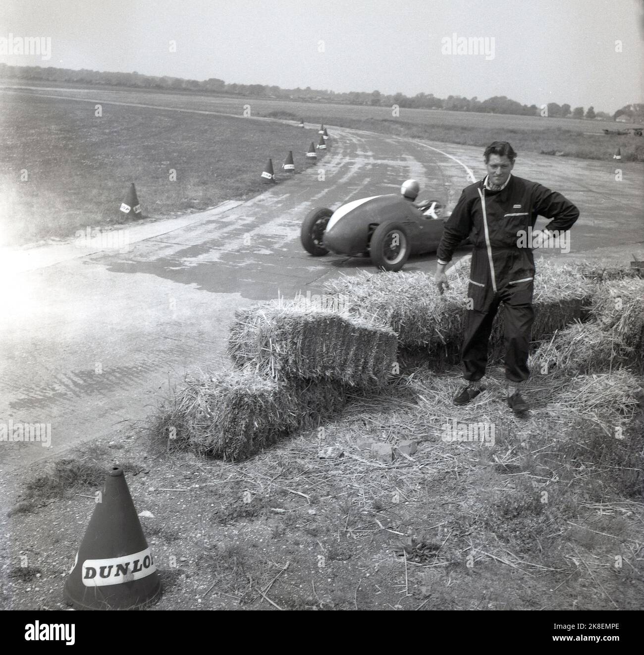 1962, historical, instructor standing by straw bales with a racing car ...