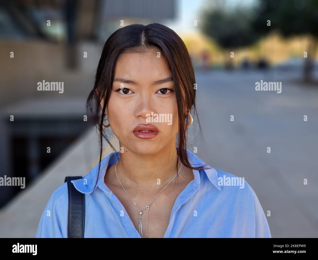 Chinese girl looking at camera with a serious expression in urban ...