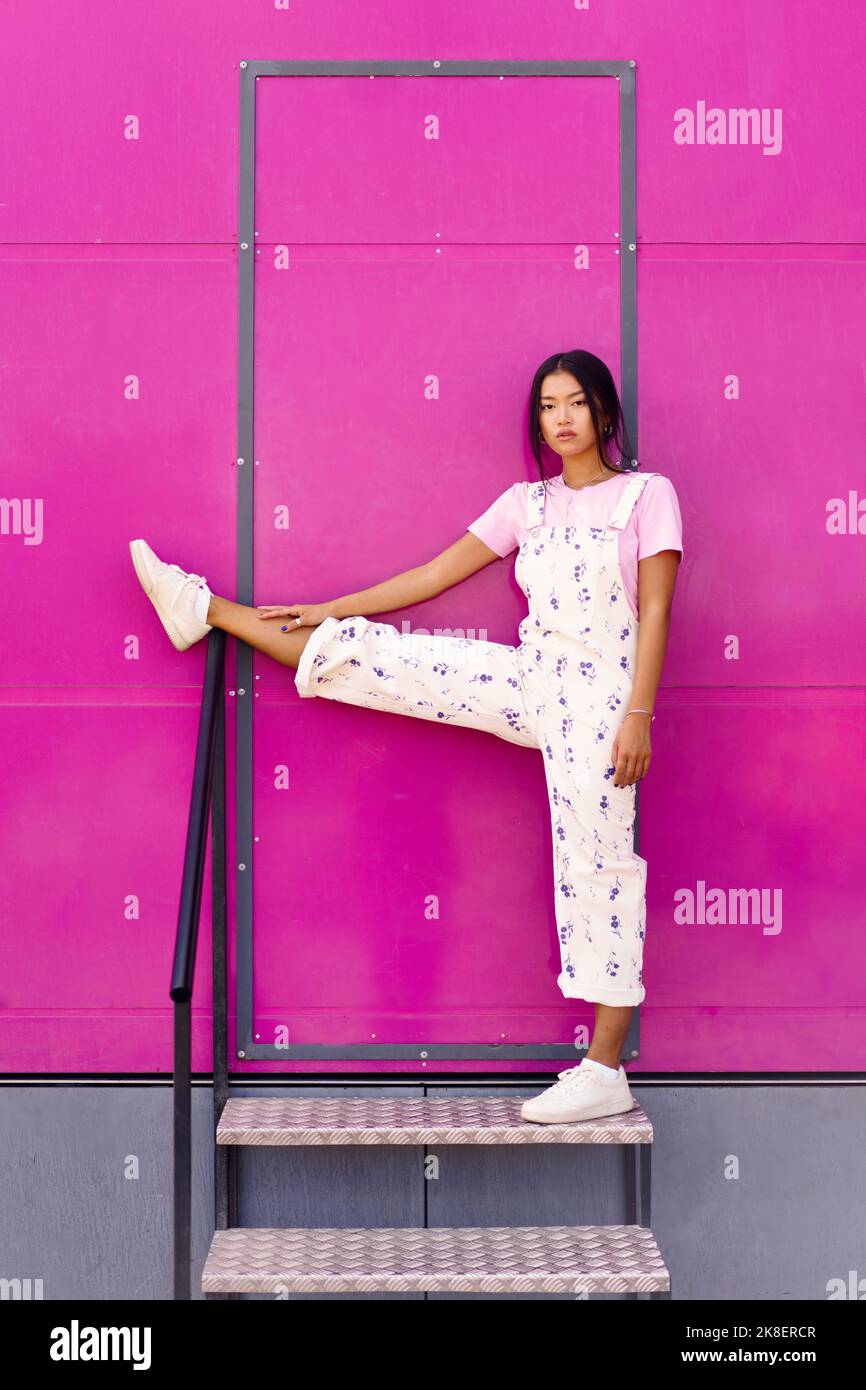 Asian woman looking at camera with serious expression, raising one leg ...