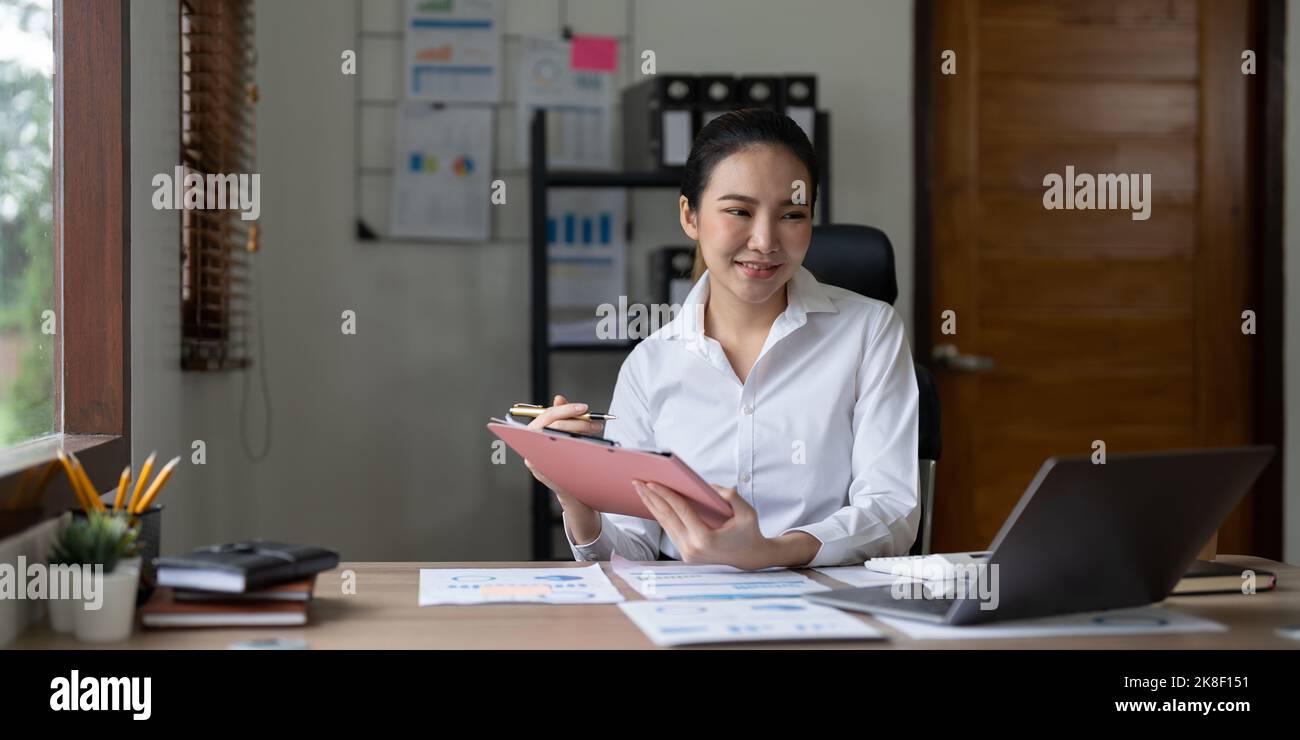 Woman accountant using calculator and laptop computer in office ...