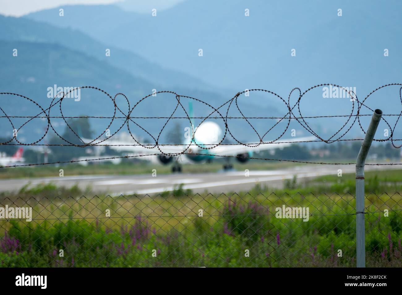 Barbed wire fence of airport against background of landing plane. Focus ...