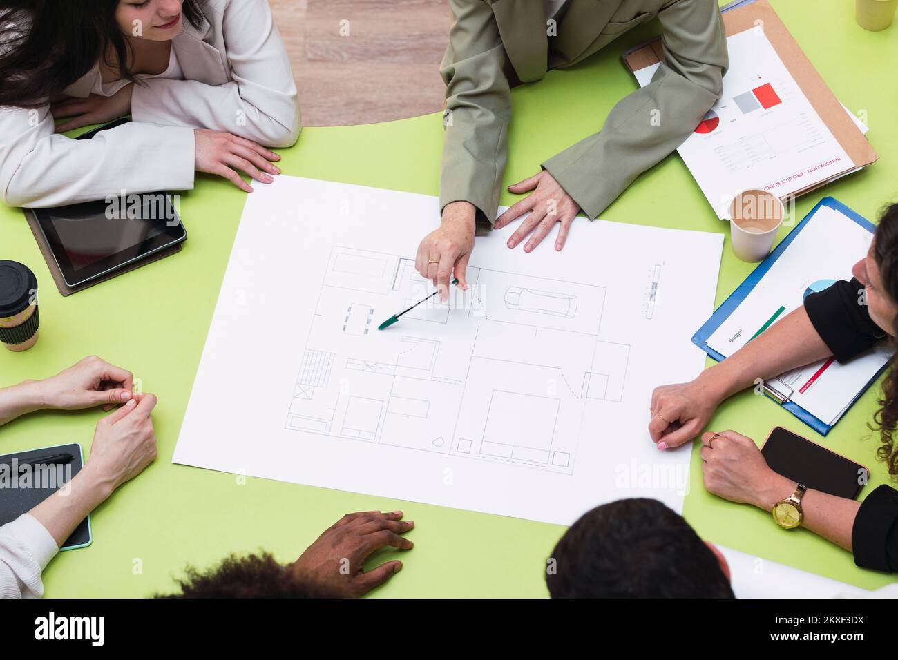 Businesswoman explaining floor plan to colleagues on table Stock Photo ...