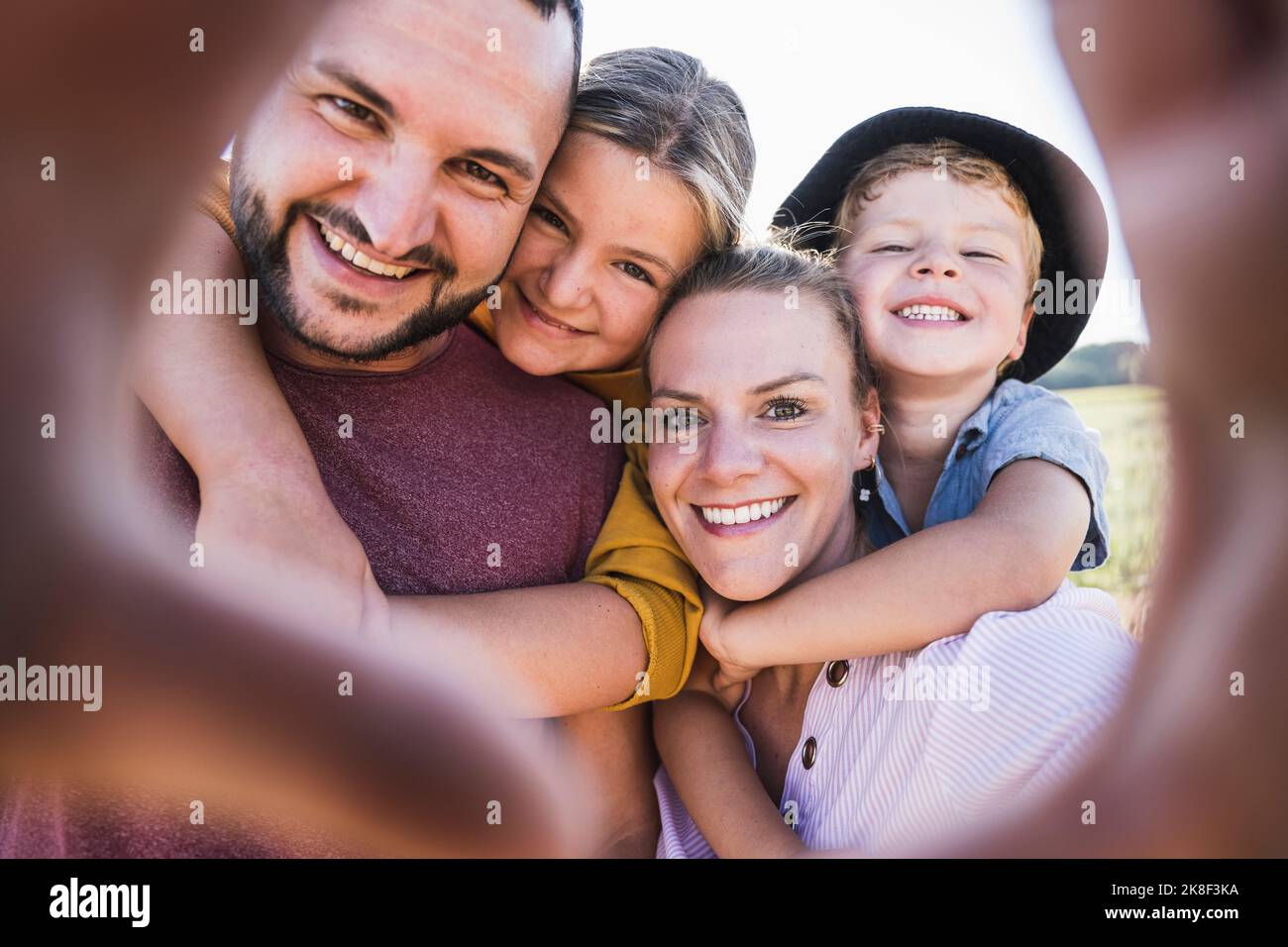 Laughing family embracing and looking through hands at camera Stock ...