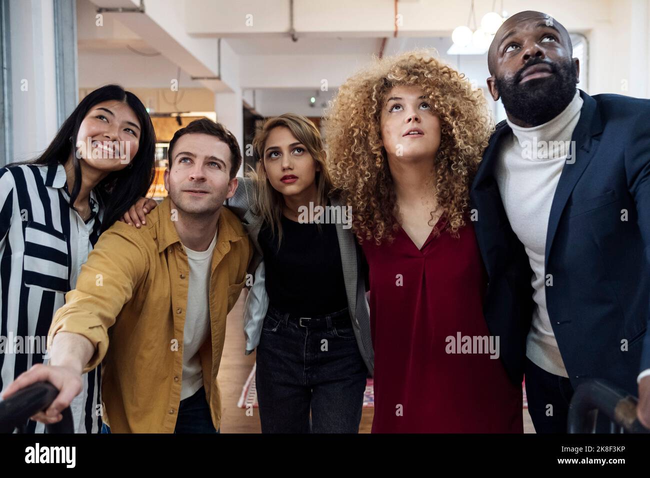 Curious young business people standing in office looking up Stock Photo ...