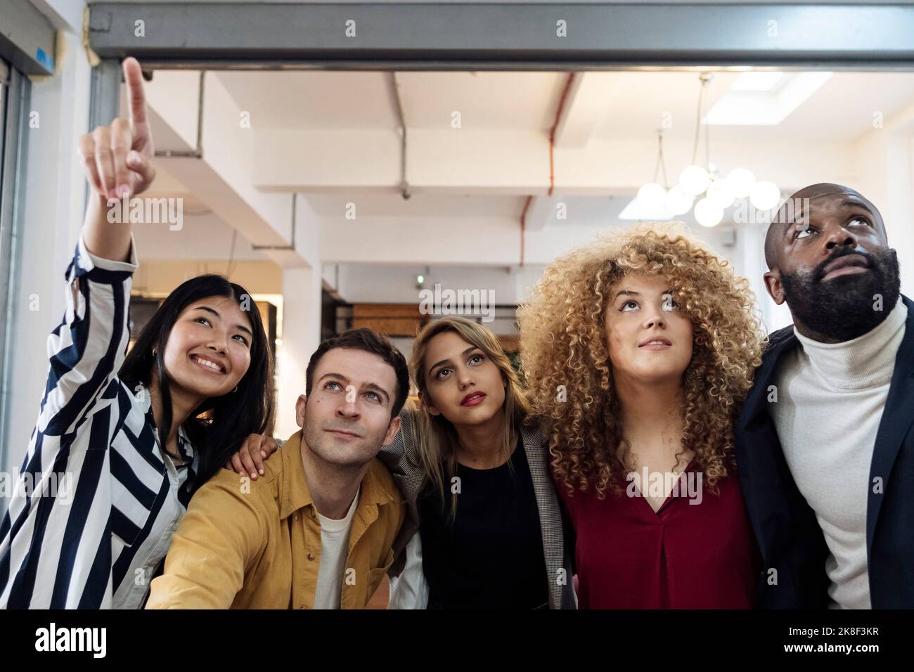 Curious young business people standing in office looking up Stock Photo ...