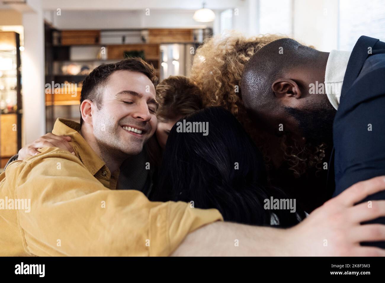 Happy business people hugging in office Stock Photo - Alamy
