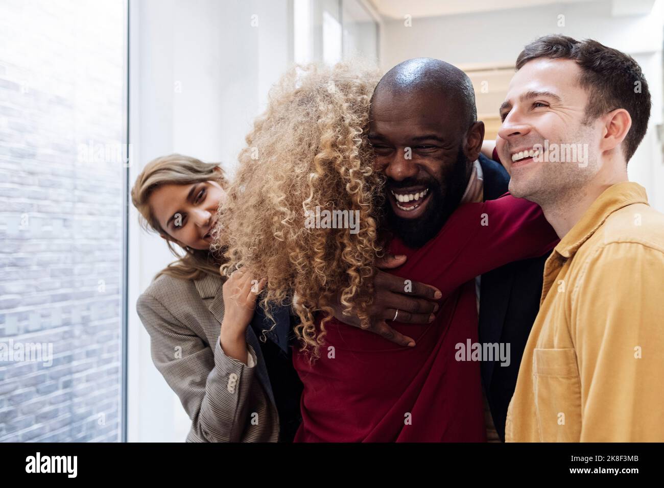 Happy business people hugging in office Stock Photo - Alamy